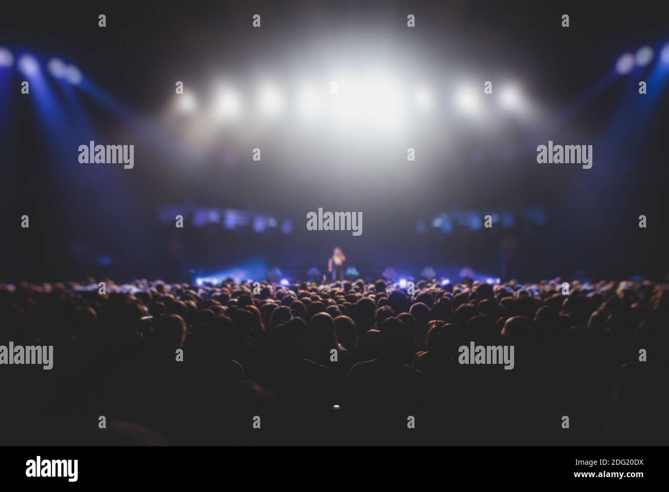 A crowded concert hall with scene stage lights, rock show performance ...