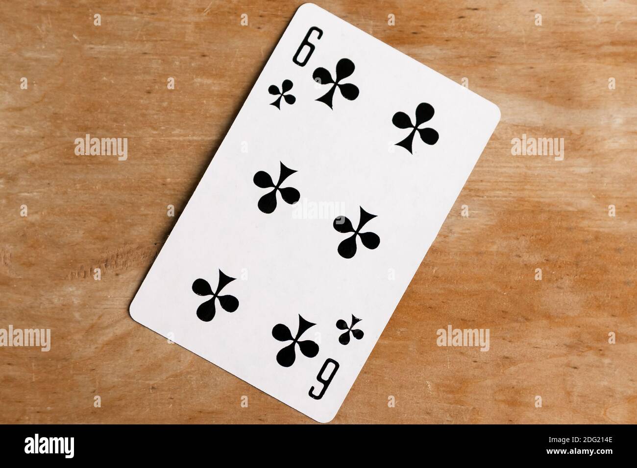 Six of Clubs playing card, wooden background Stock Photo - Alamy