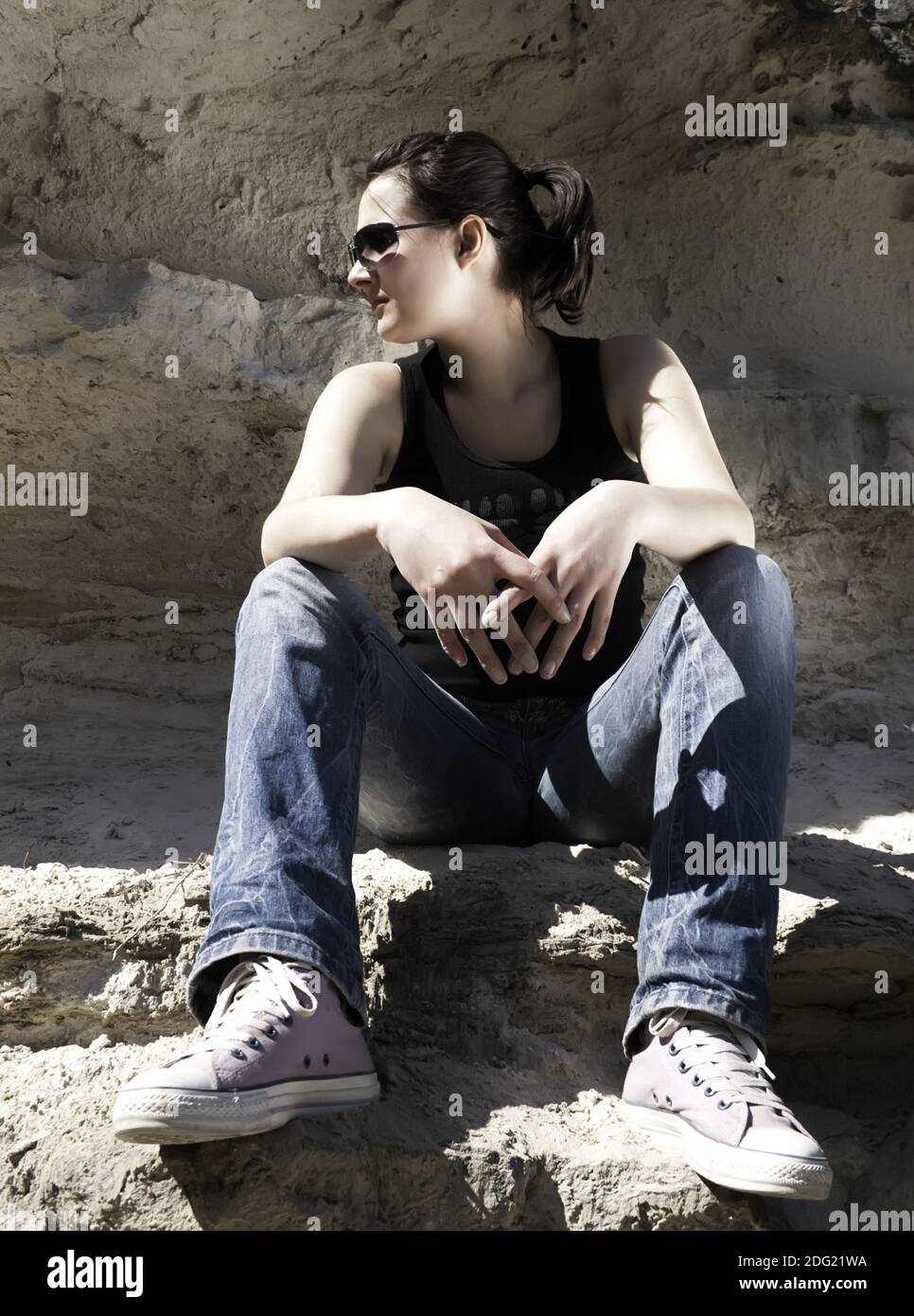 Model sitting on the rocks. Urban style Stock Photo - Alamy