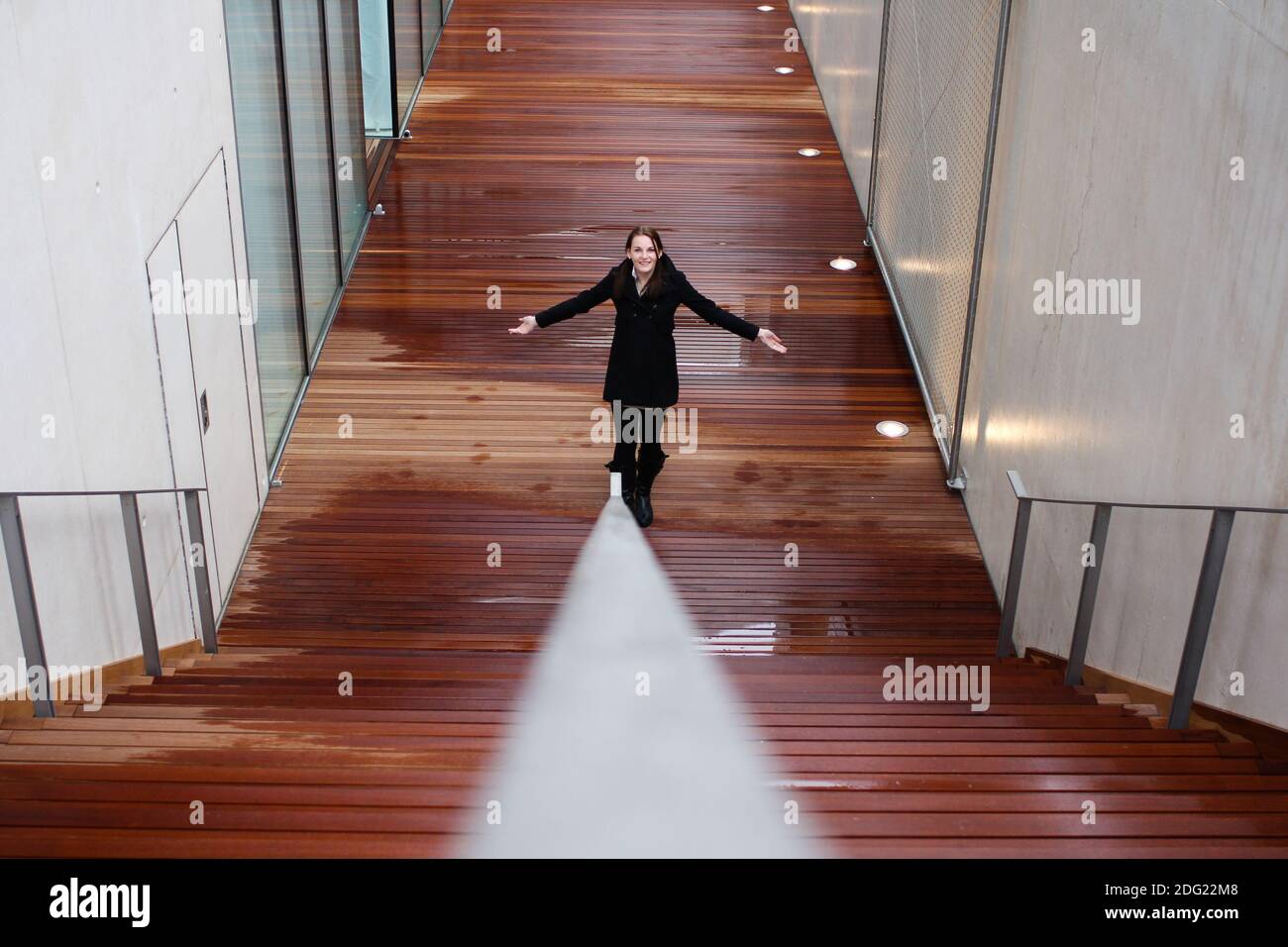 Young woman standing with hands apart on a wooden floor Stock Photo - Alamy