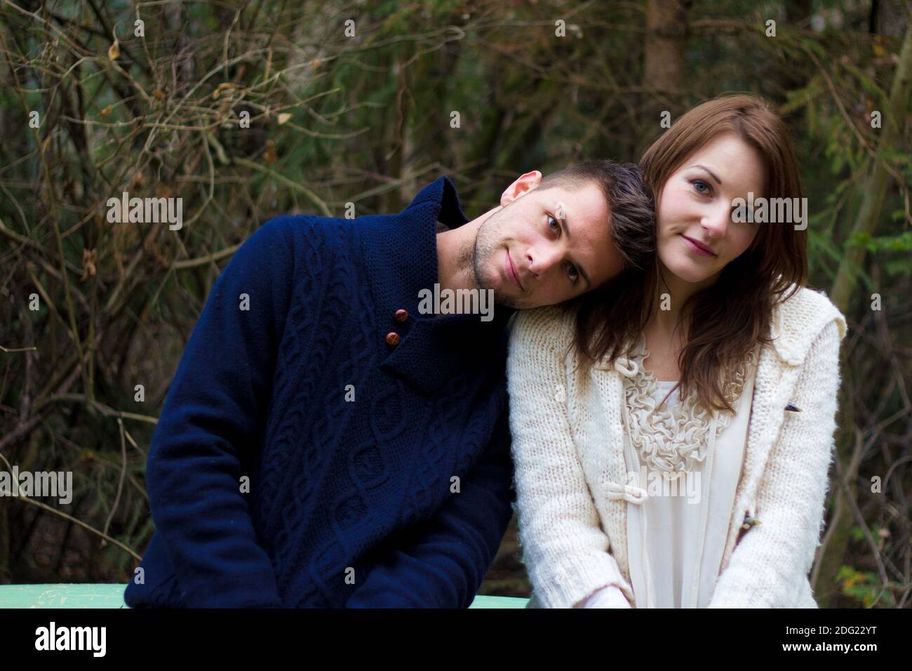 Young couple in the forest head on head in front of trees and plants ...