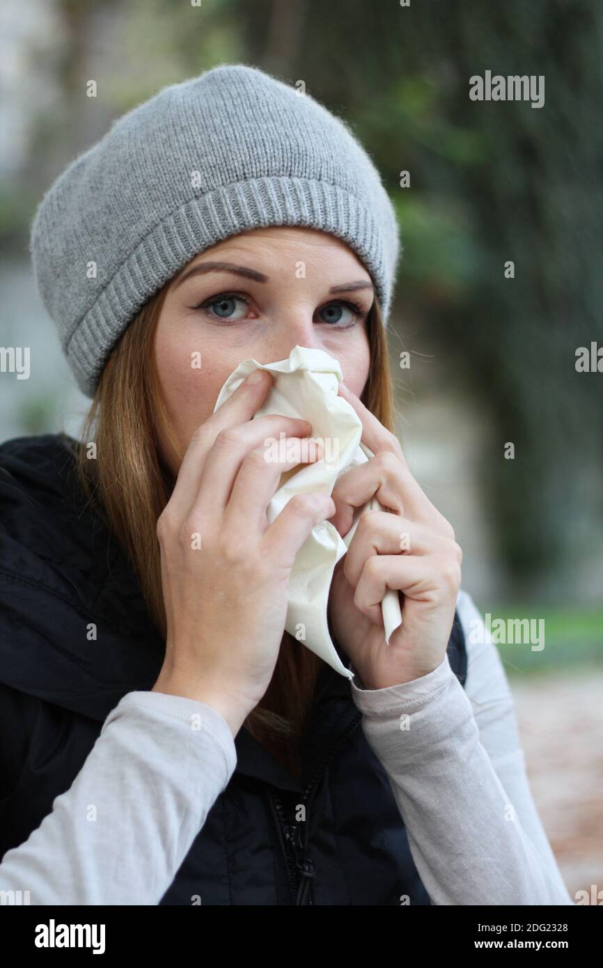 Woman blowing into tissue Stock Photo - Alamy