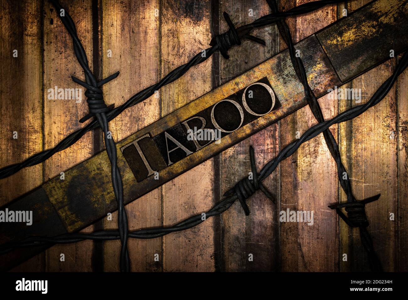 Taboo text lined with barbed wire on grunge textured bronze background ...