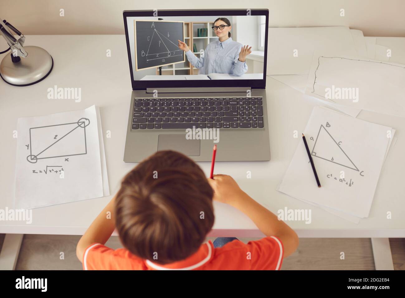 Boy making notes during online geometry lesson with teacher Stock Photo ...