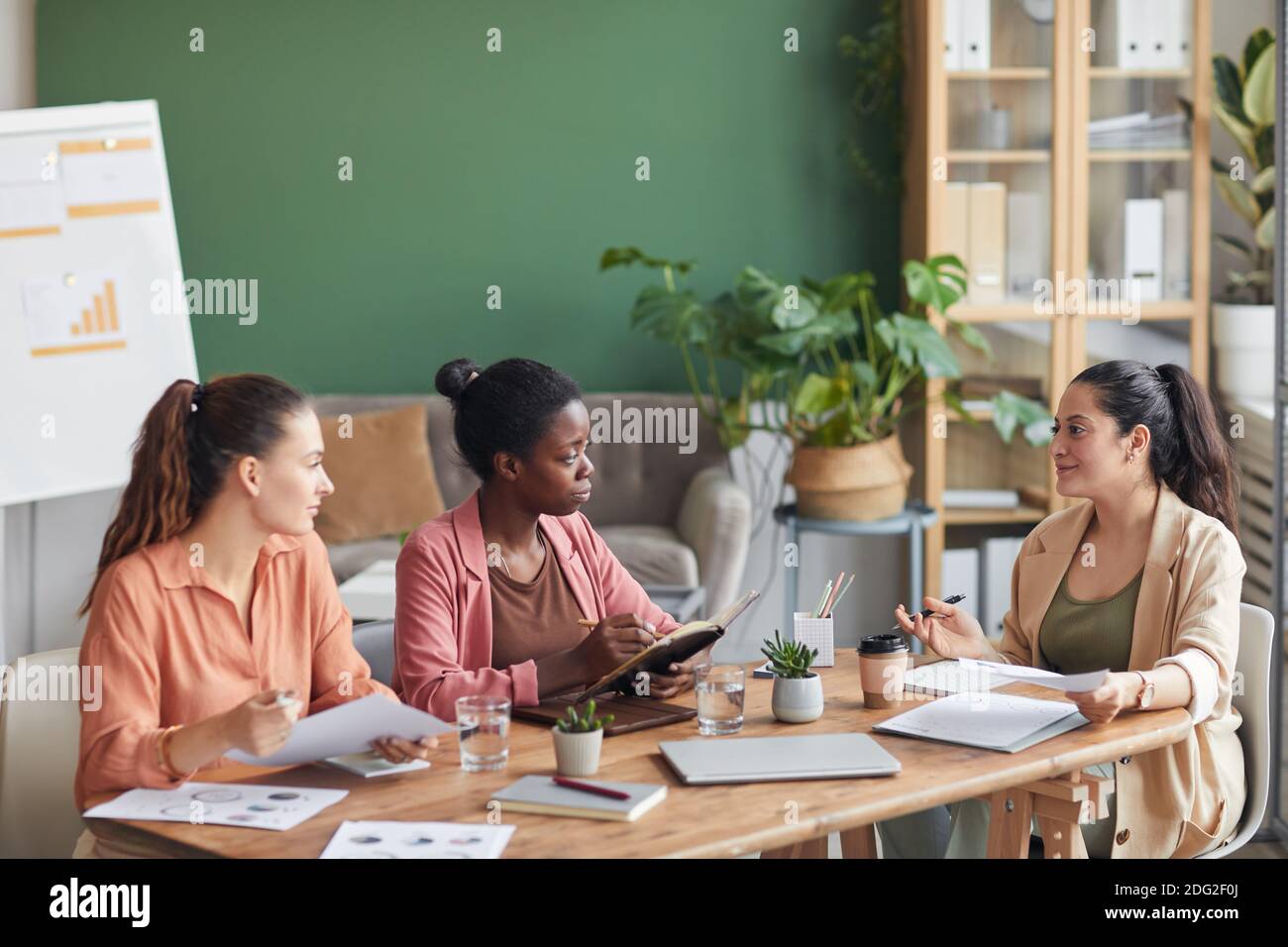 Portrait of female business team discussing project while sitting at ...