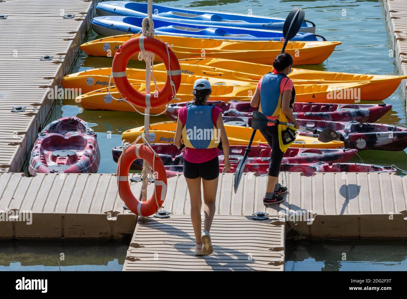 Two women walking towards a jetty to kayak Stock Photo - Alamy