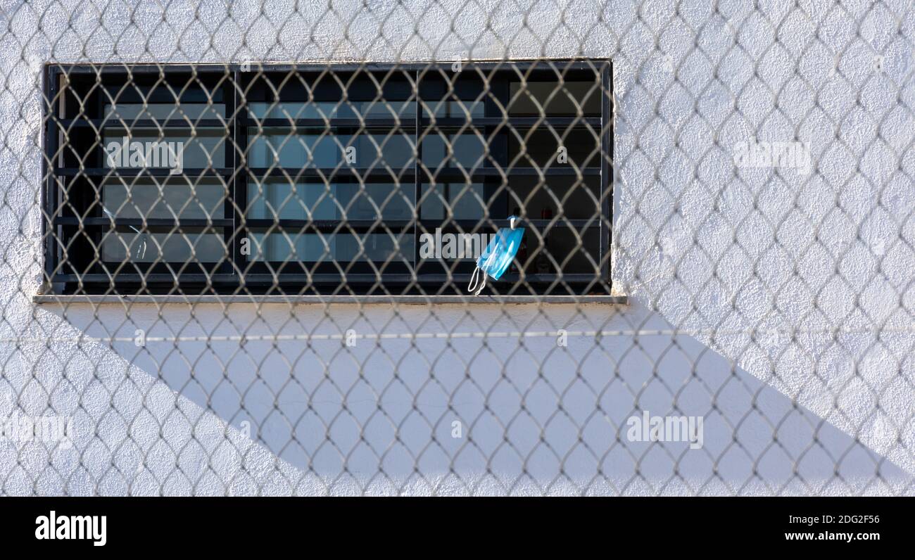 Face mask tied to the bars of a window behind a metallic fence Stock ...