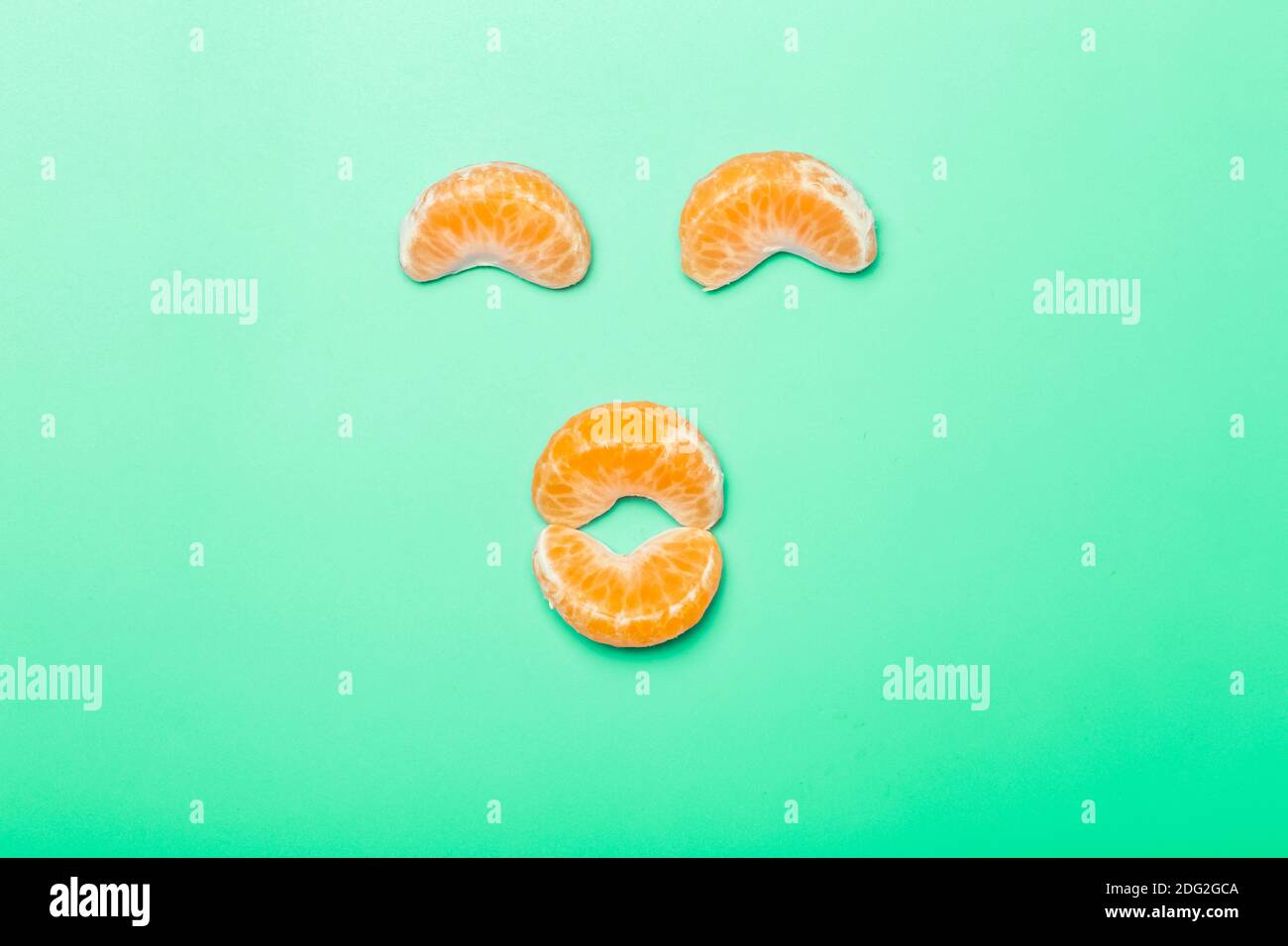 Tangerine slices on a blank colored minimal background. Funny face made ...