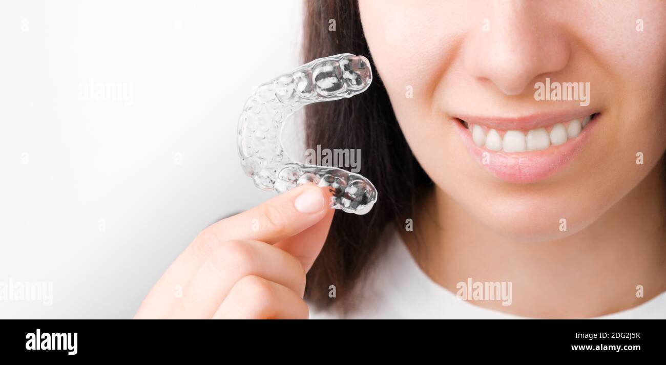 Close up woman holding a transparent removable braces for perfect smile ...