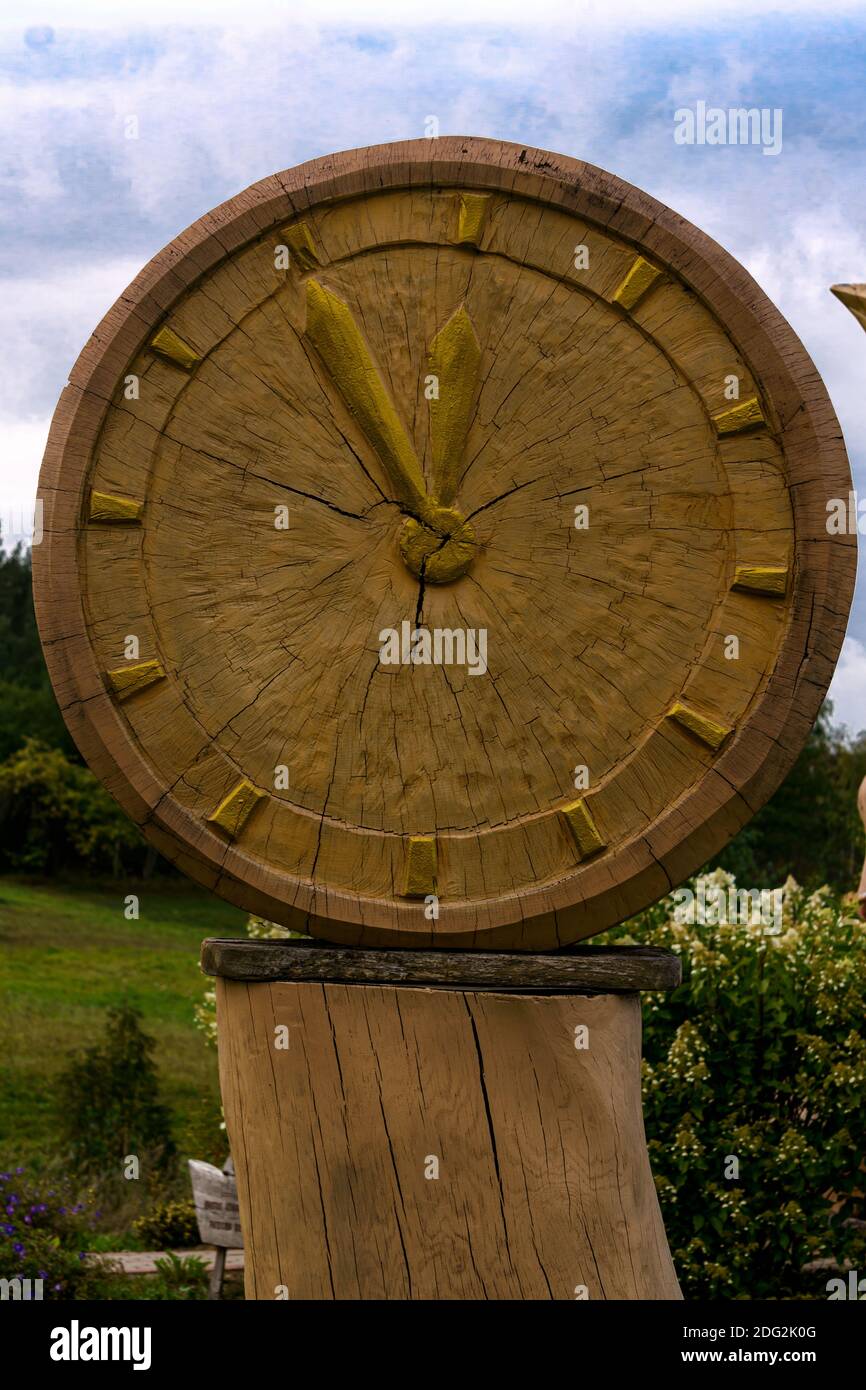Stylized sculpture of a clock from a thick dry trunk of an old tree ...
