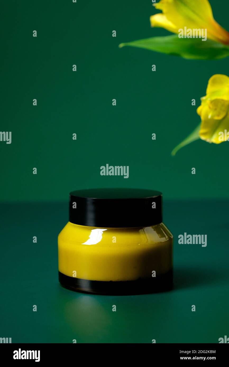 Herbal cream moisturizer jar with flowers on green background. Organic ...