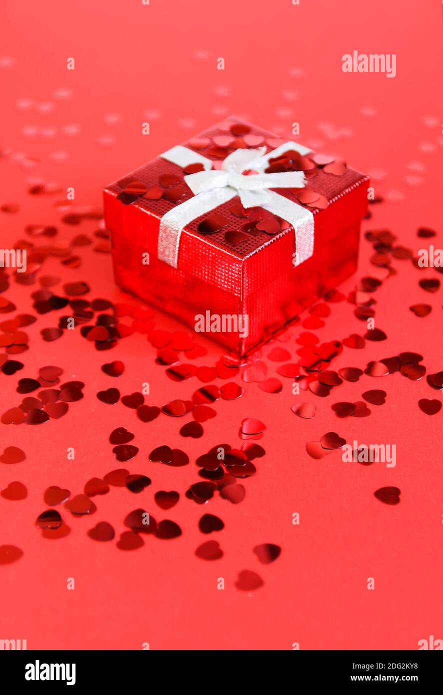 Small red gift box with silver ribbon on bright background with ...