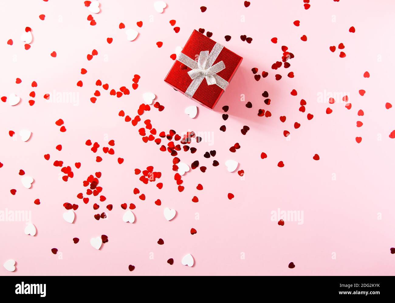 Small red gift box on soft pink pastel background with decorative small ...