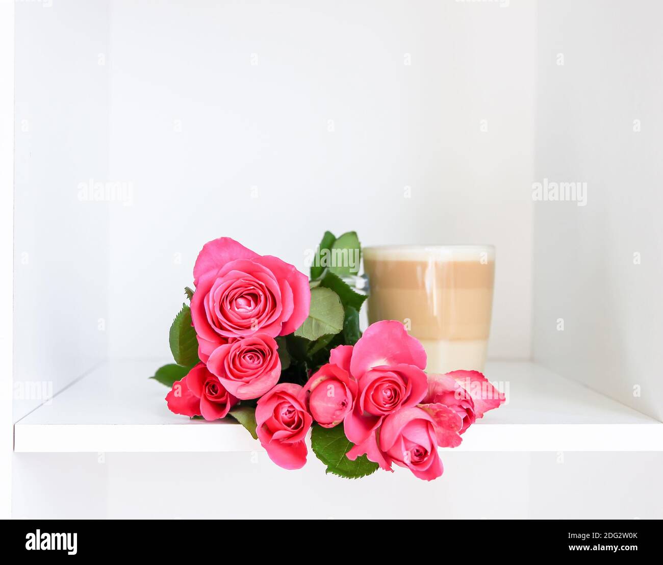 Beautiful pink roses bouquet and the transparent glass cup of hot latte ...