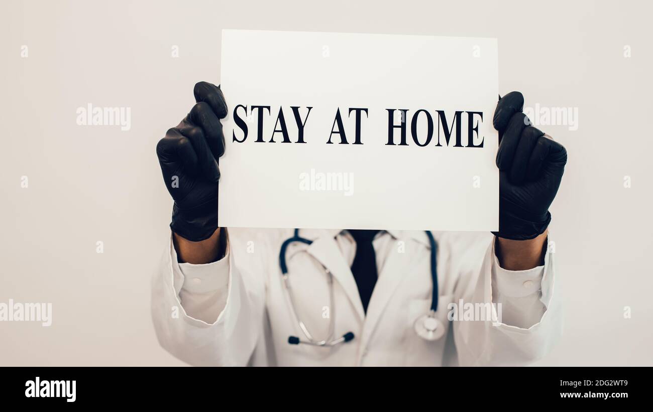 warning stay at home in the hands of the doctor Stock Photo - Alamy