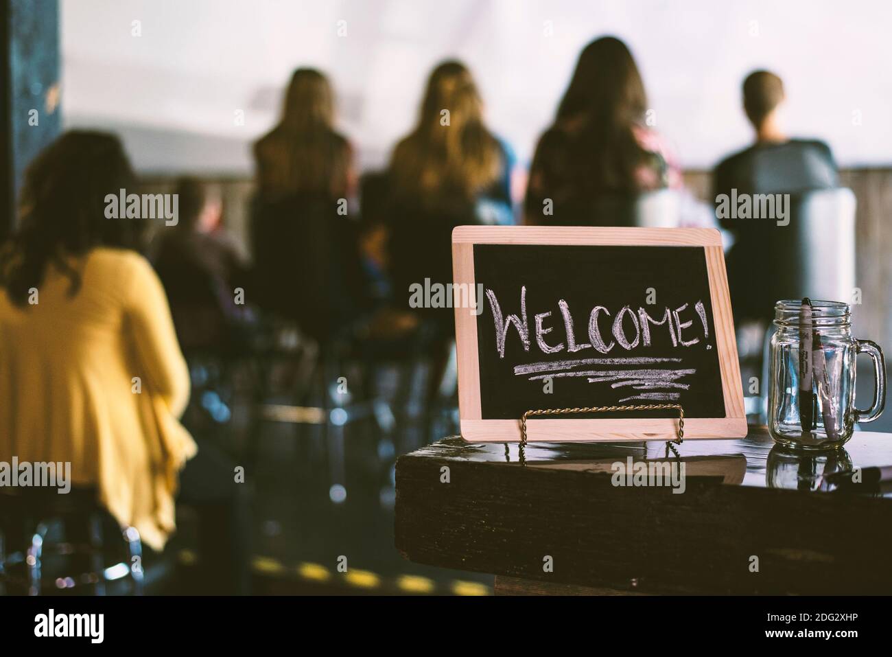 Welcome sign behind a group meeting Stock Photo - Alamy