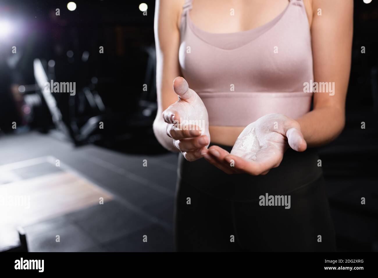 partial view of sportswoman applying talcum powder on hands in sports ...