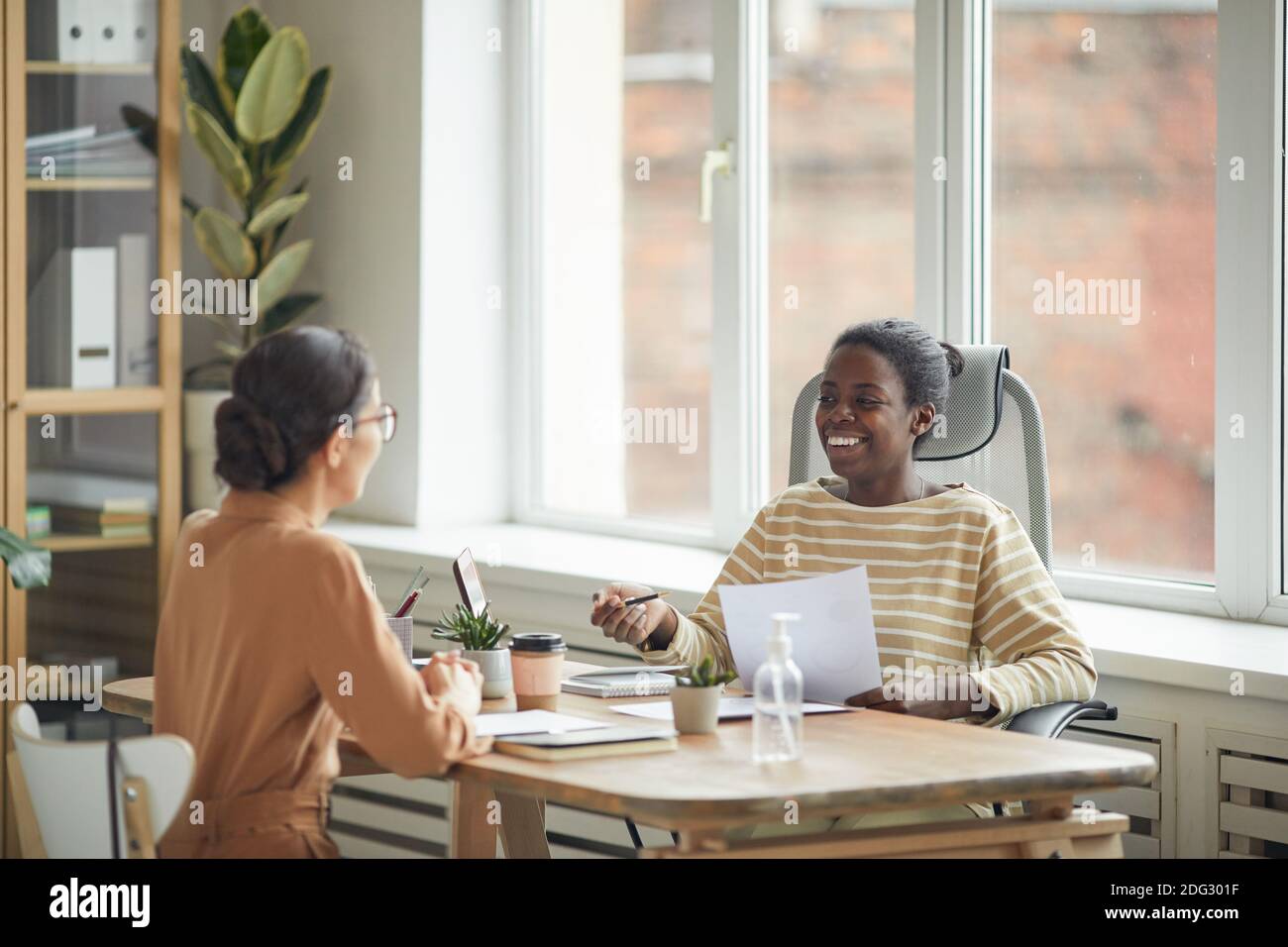 Portrait of smiling African-American woman talking to young woman ...