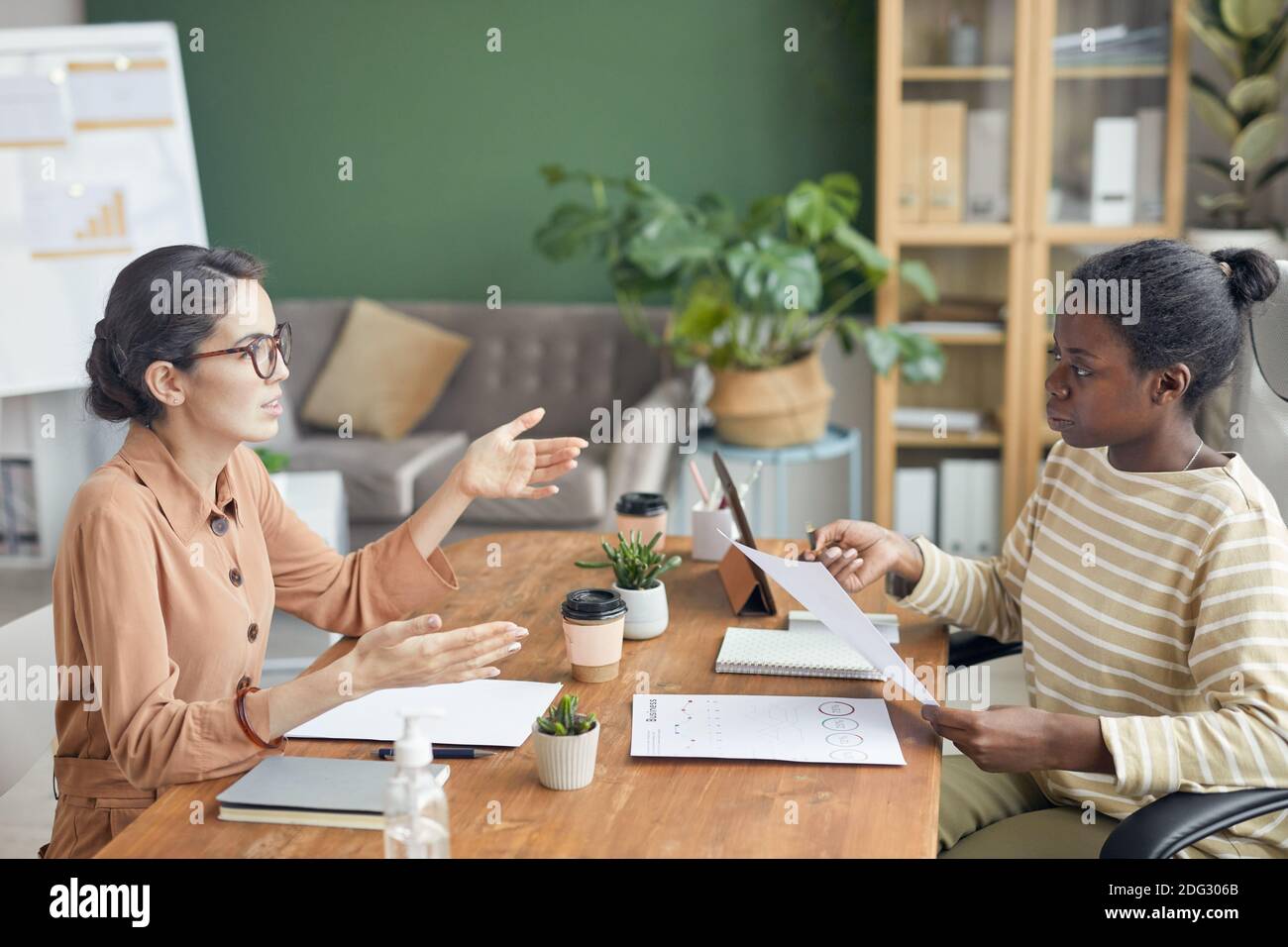 Side view portrait of two businesswomen talking and gesturing during ...