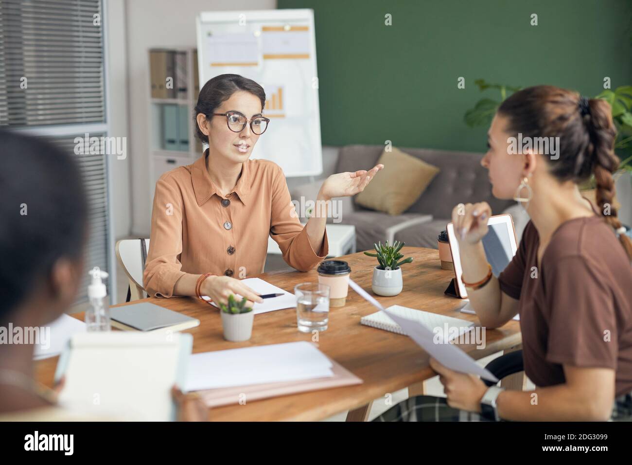 Group of modern female entrepreneurs talking animatedly during business ...