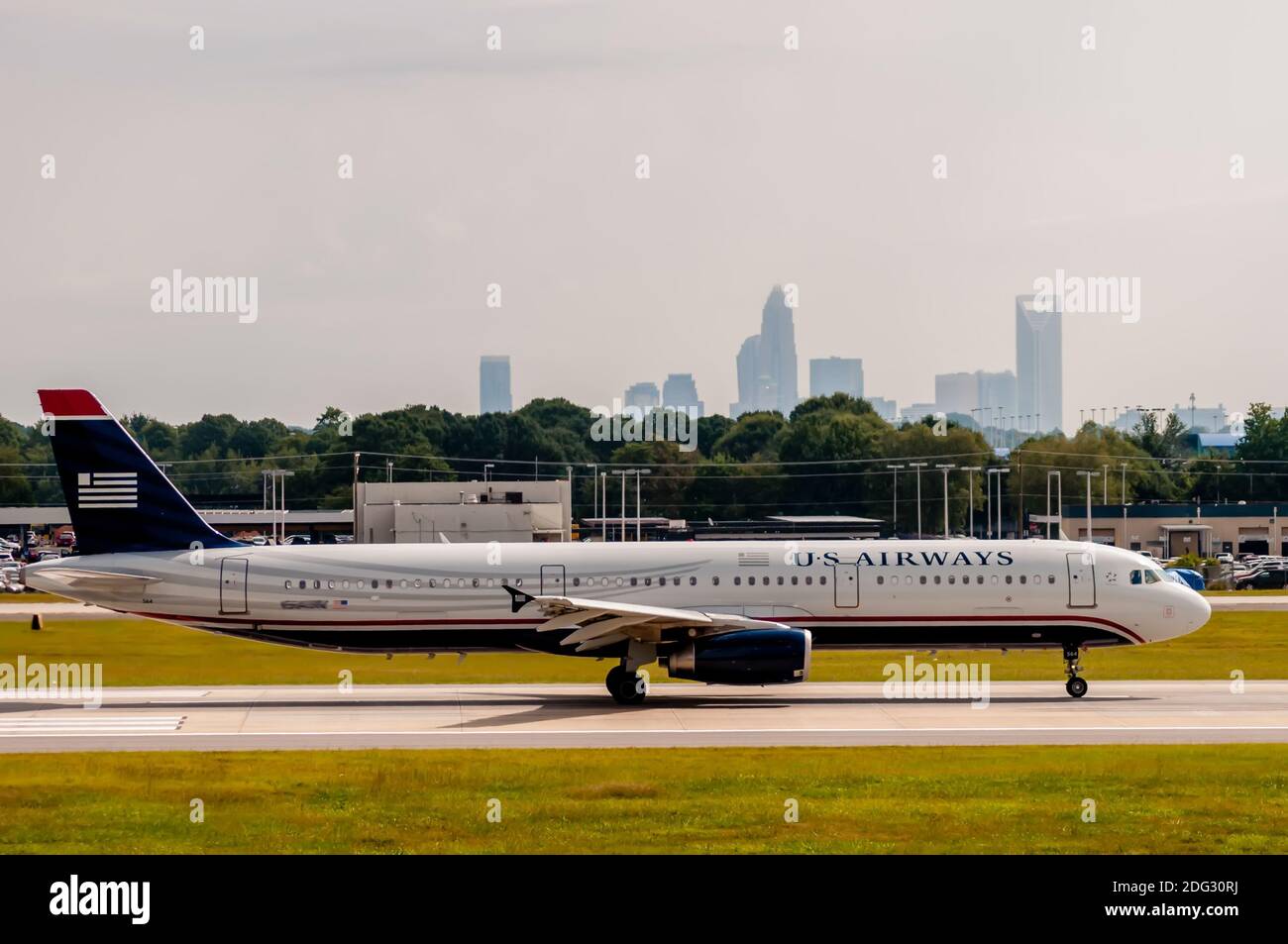 Commercial jet on an airport runway with city skyline in the background ...