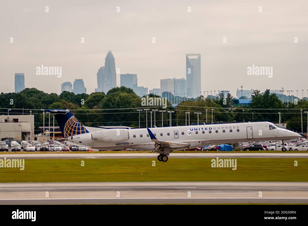 Commercial jet on an airport runway with city skyline in the background ...