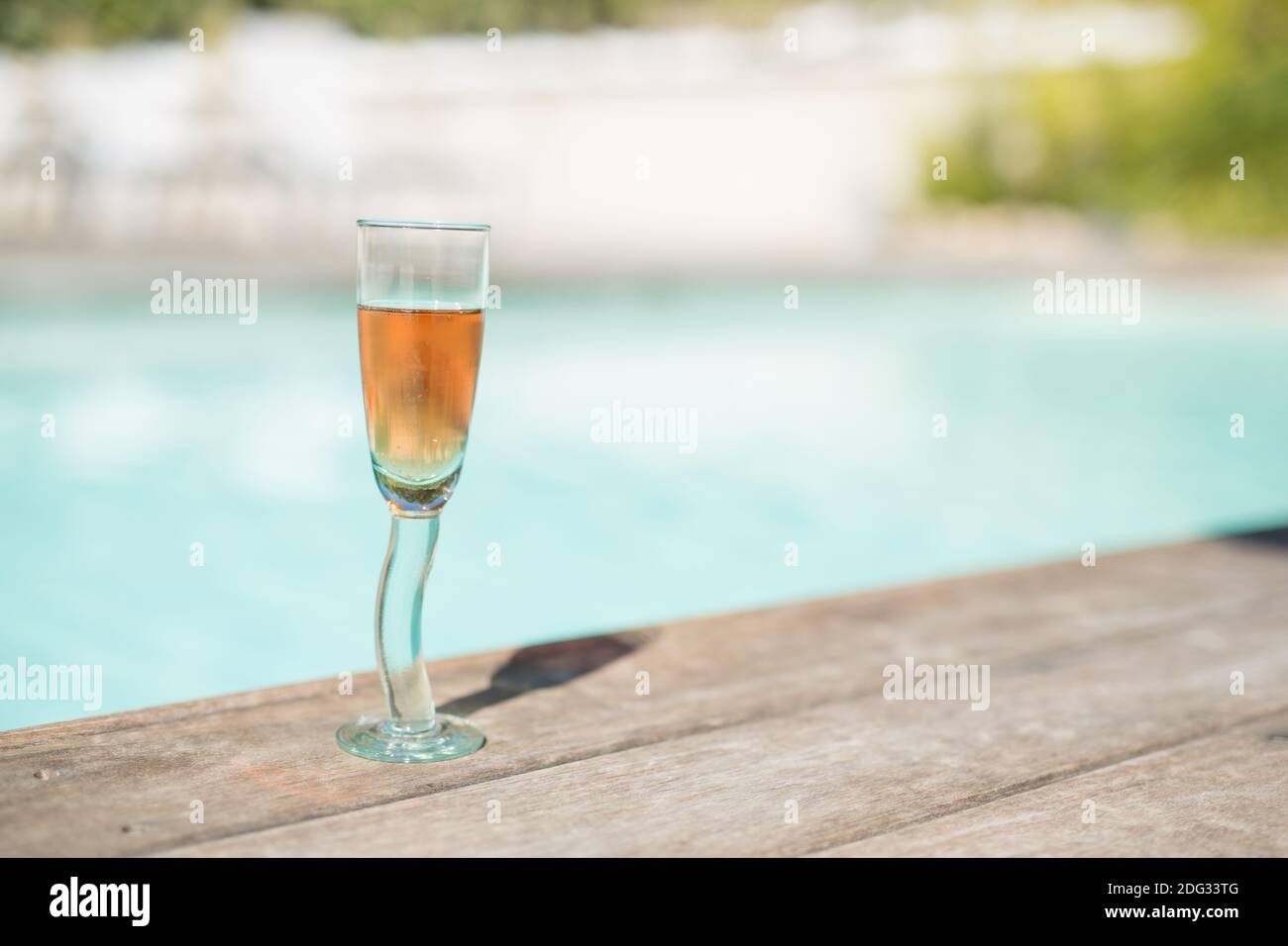 Glass of rosé wine at the edge of a swimming pool with a blurred bottom ...