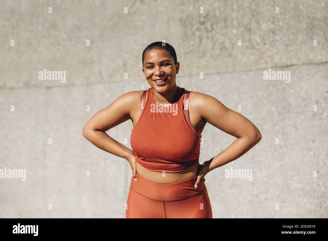 Smiling plus size woman sportswear standing with her hands on hips ...