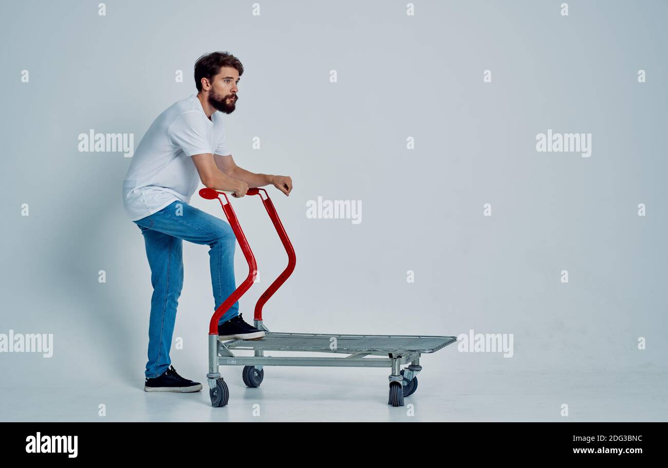 man with a trolley in his hand on a light background transporting heavy ...