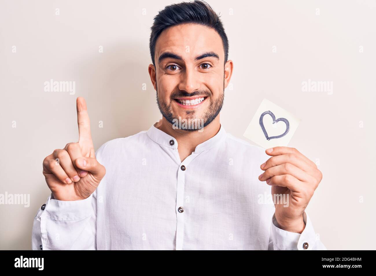 Young handsome romantic man with beard holding reminder with heart ...