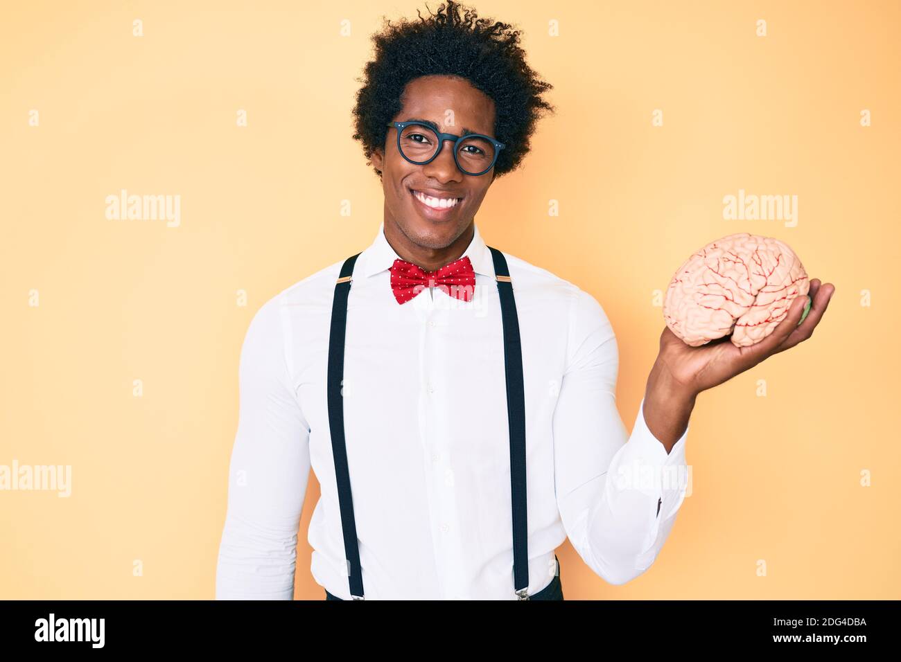 Handsome african american nerd man with afro hair holding brain looking ...