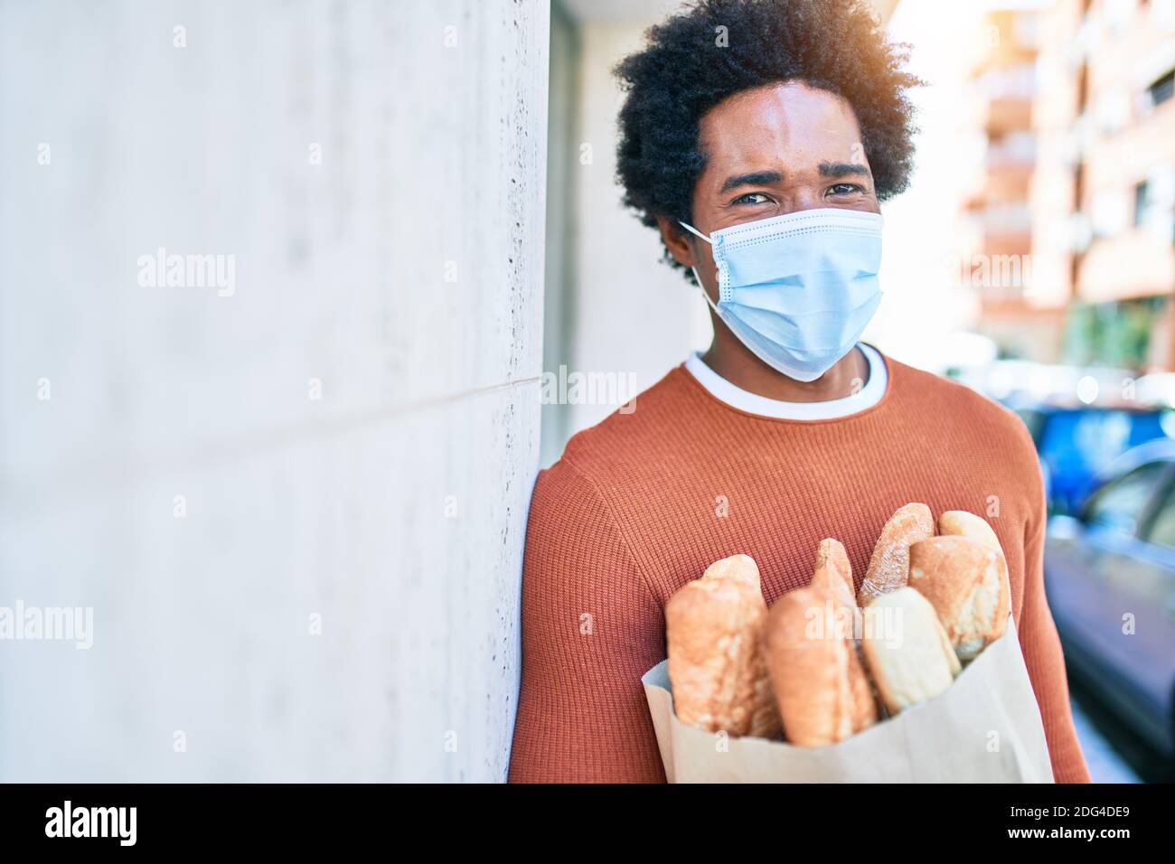 Young handsome african american man wearing medical mask. Leaning on ...