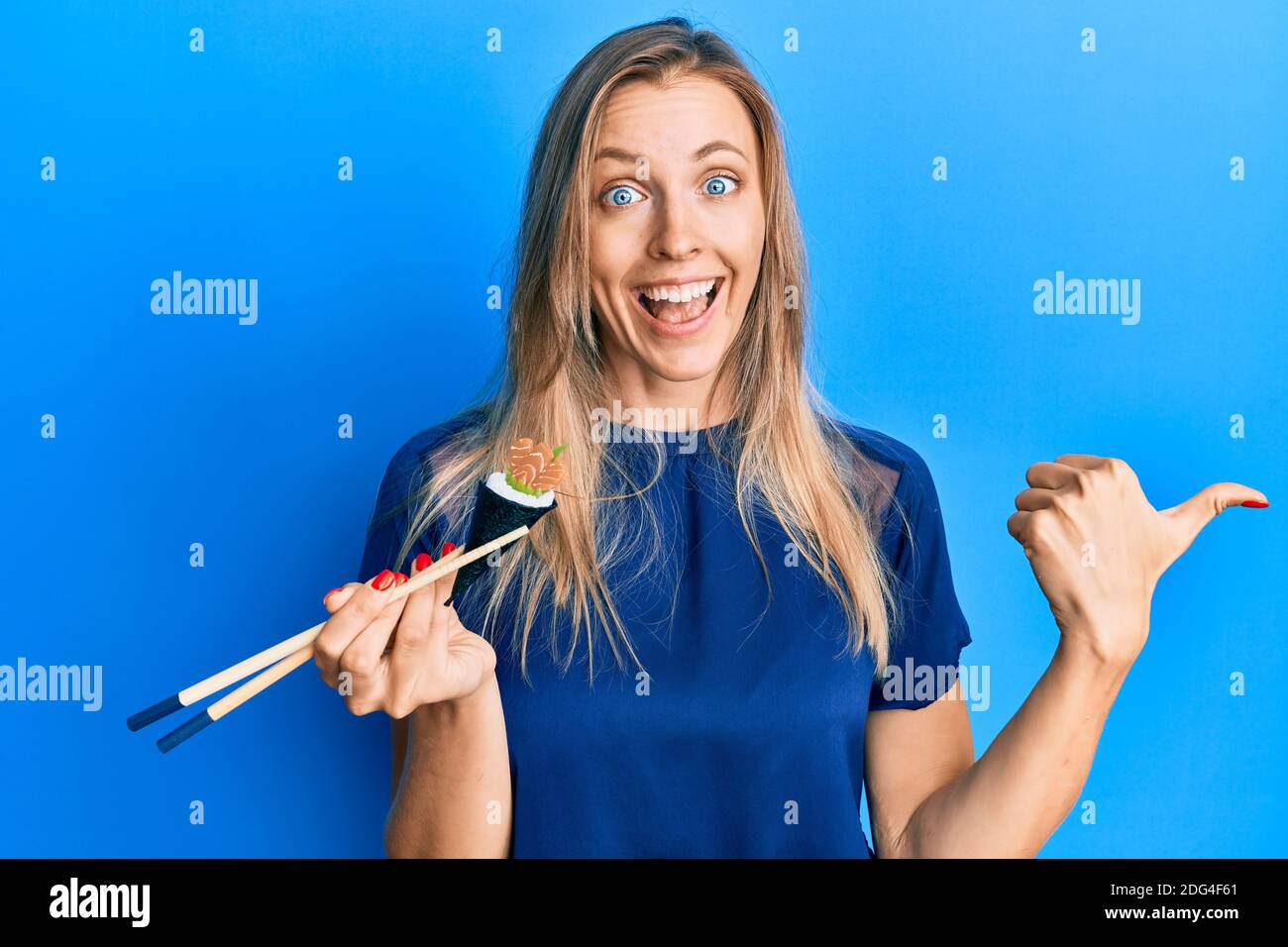 Beautiful caucasian woman eating temaki sushi using chopsticks pointing ...