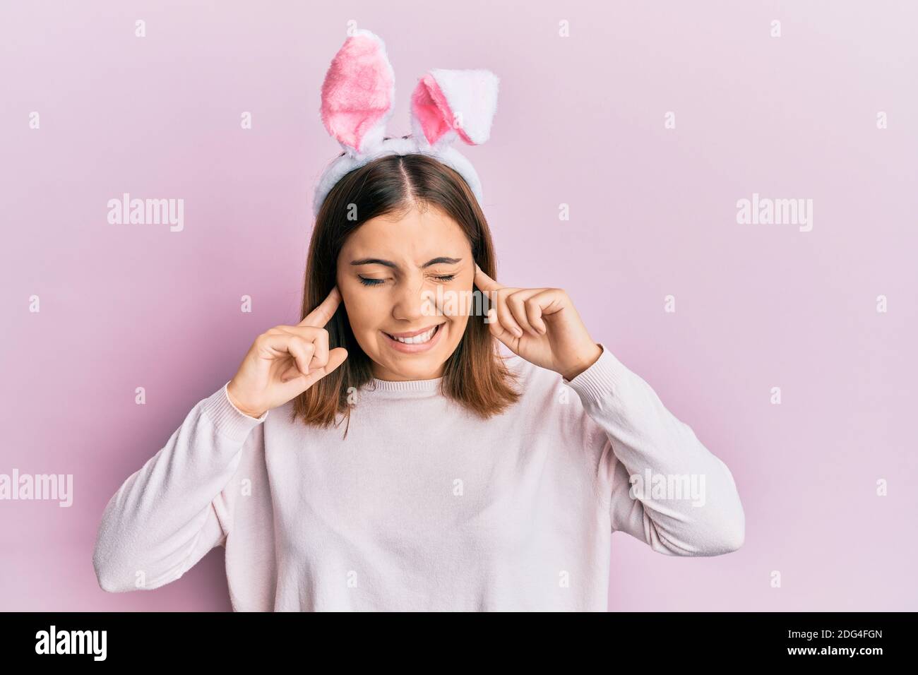 Young beautiful woman wearing cute easter bunny ears covering ears with ...