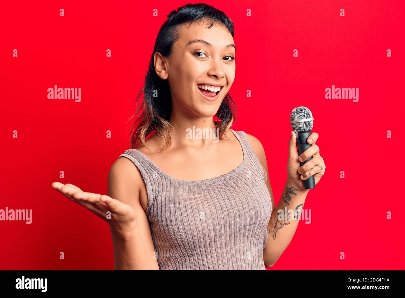 Young woman singing song using microphone celebrating achievement with ...