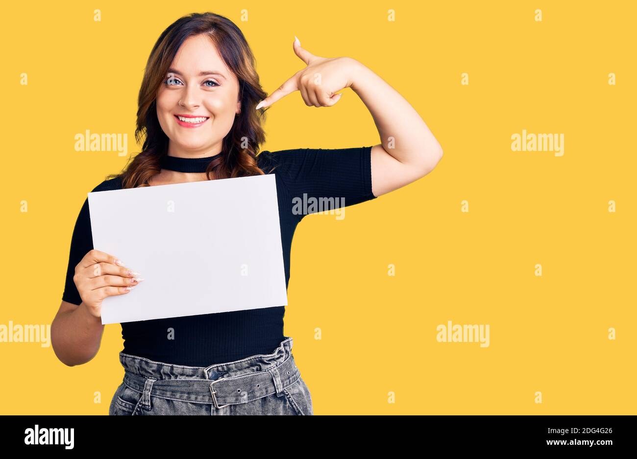 Young beautiful caucasian woman holding blank empty paper pointing ...