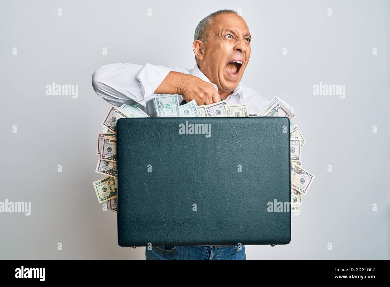 Handsome senior man holding briefcase full of dollars angry and mad ...