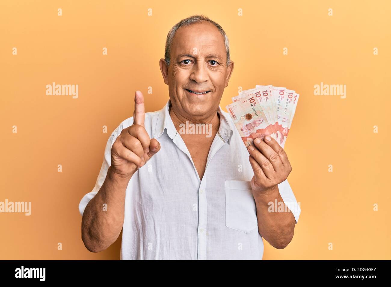 Handsome mature man holding 10 colombian pesos banknotes smiling with ...