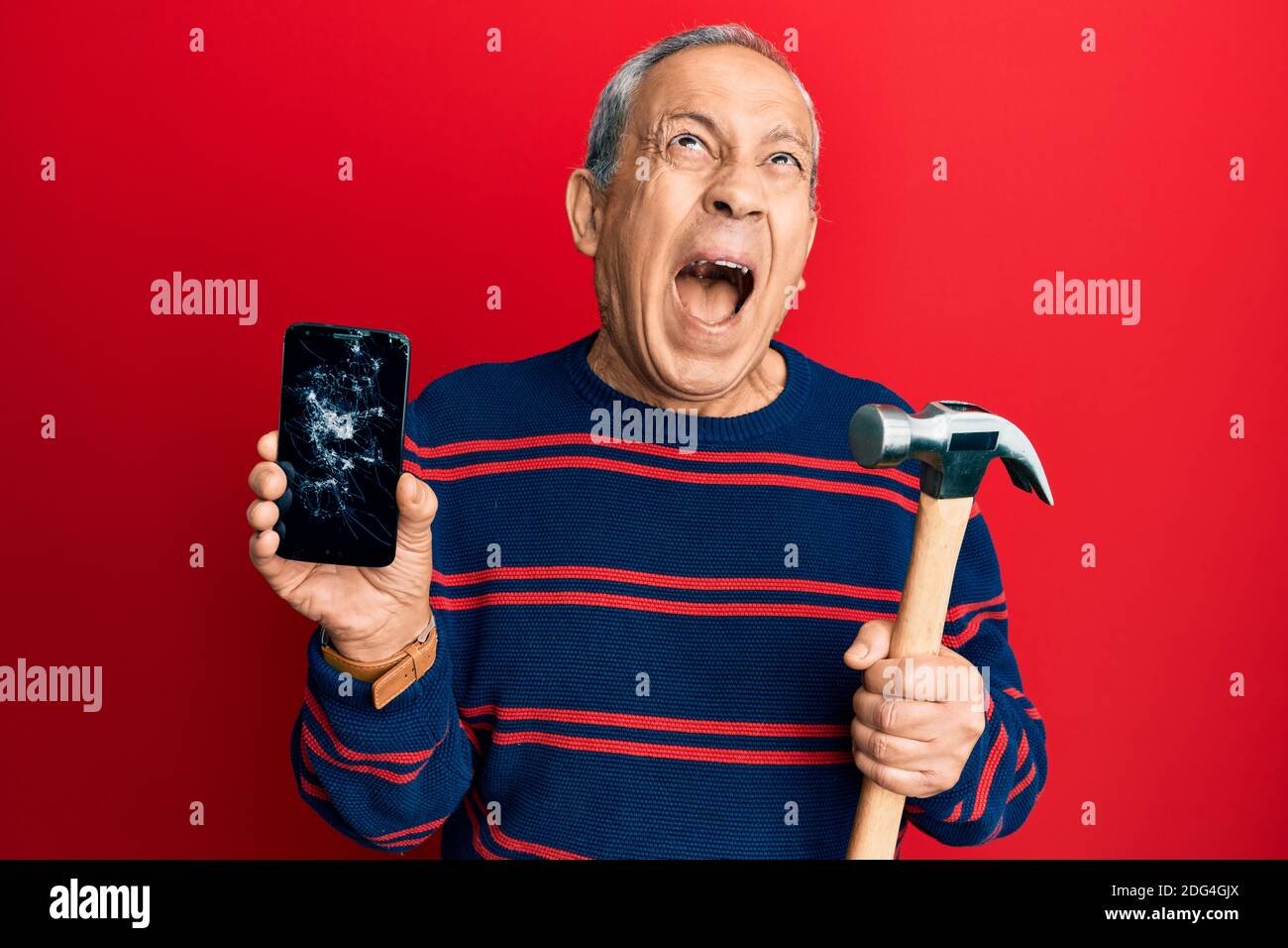 Senior hispanic man holding broken smartphone showing cracked screen ...