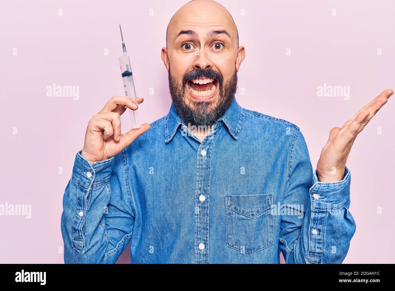 Young handsome man holding syringe celebrating victory with happy smile ...