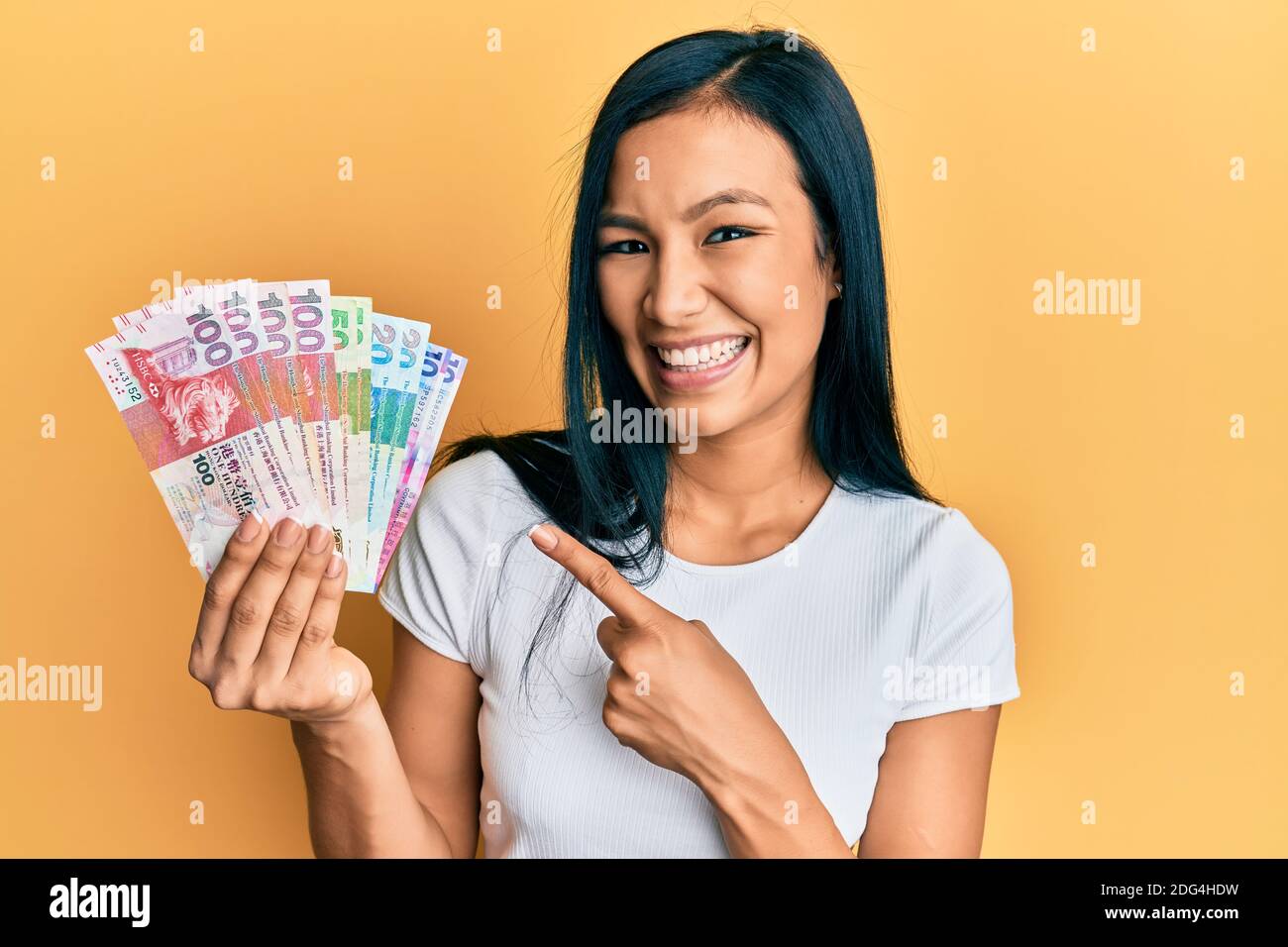 Beautiful hispanic woman holding hong kong dollars banknotes smiling ...