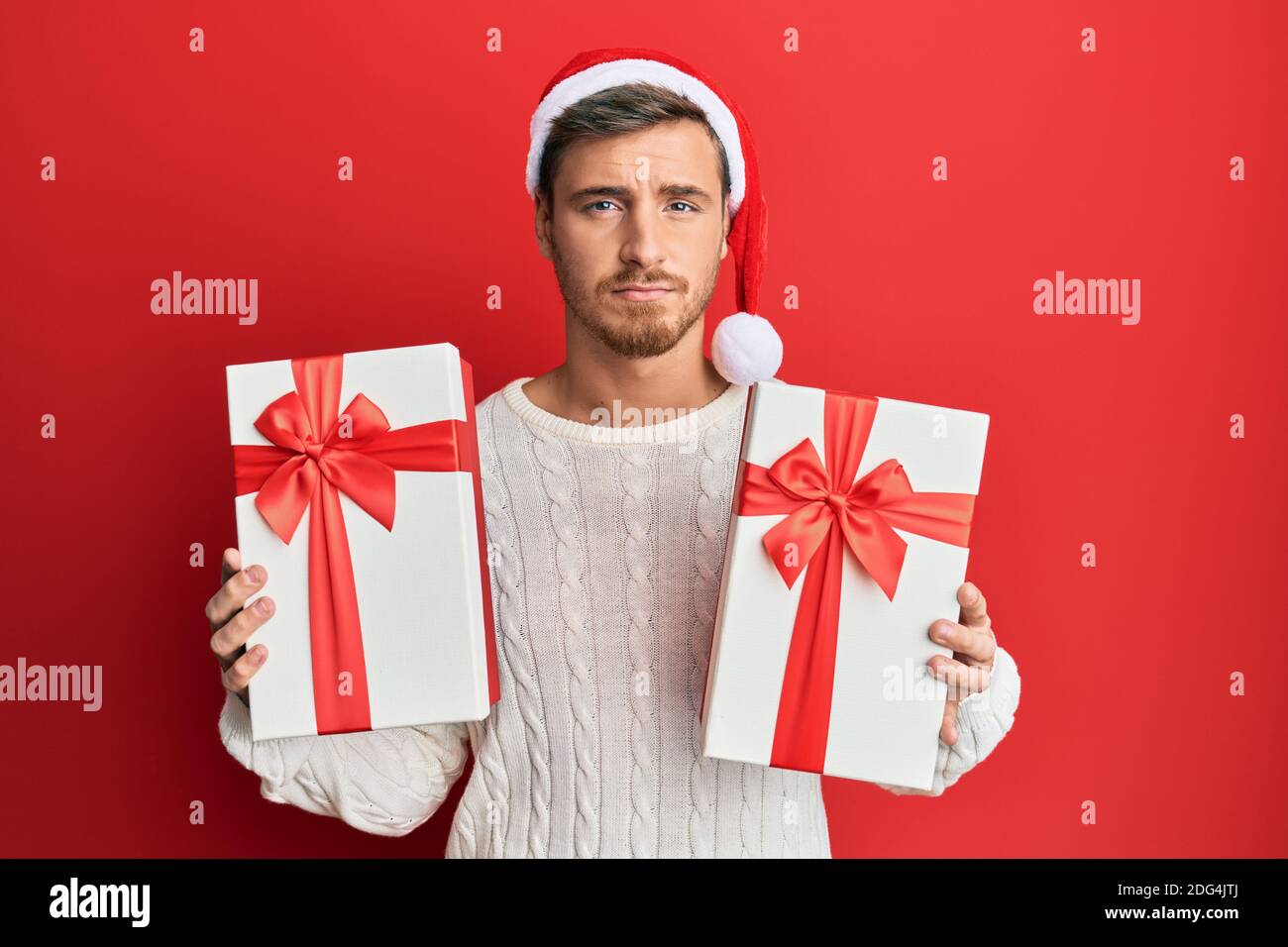 Handsome caucasian man wearing christmas hat and holding gifts ...