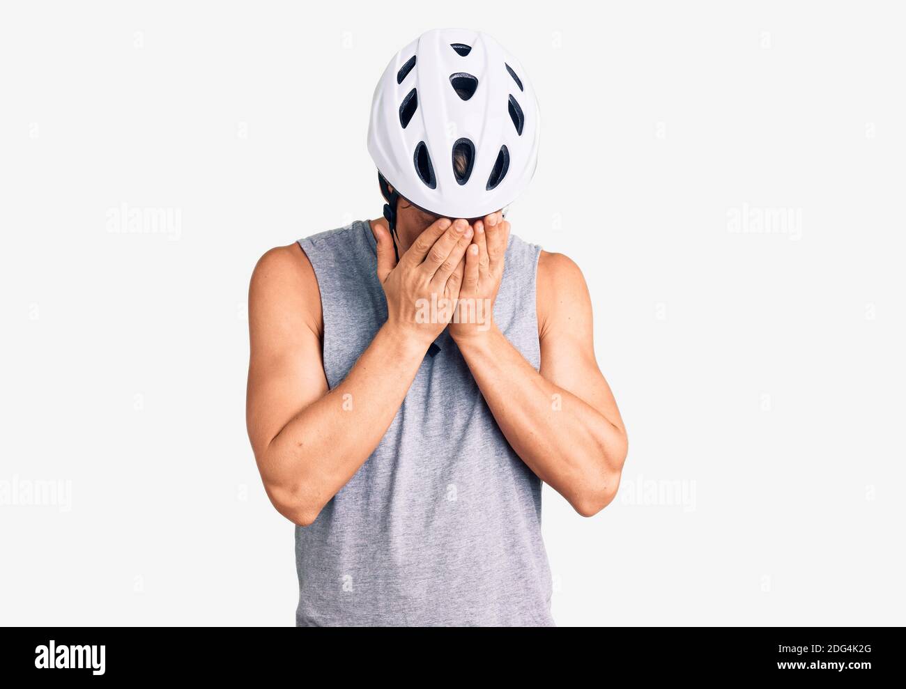 Young handsome man wearing bike helmet with sad expression covering ...