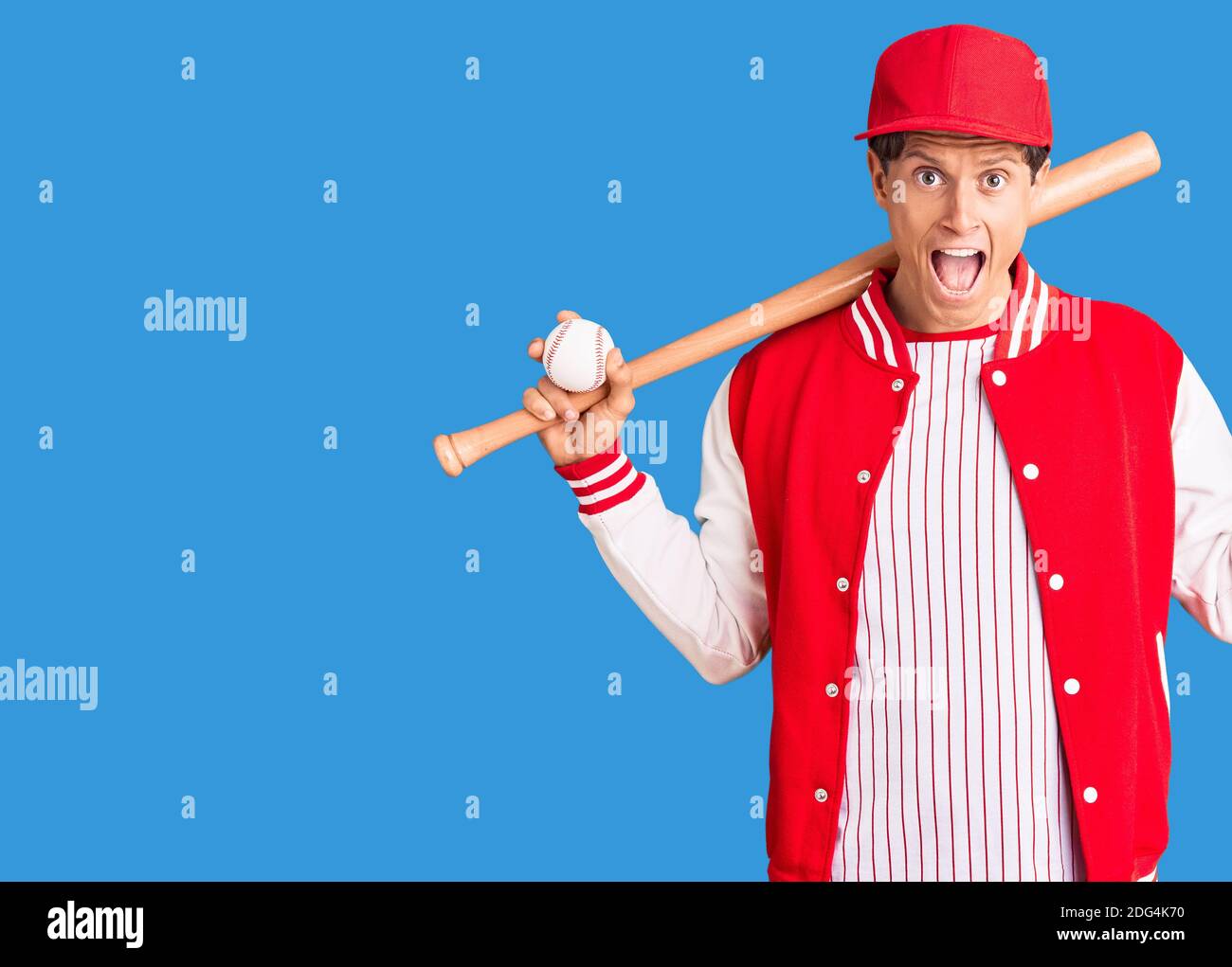 Young handsome man playing baseball holding bat and ball screaming ...