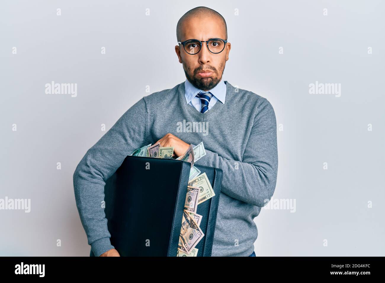 Hispanic adult man holding briefcase full of dollars depressed and ...