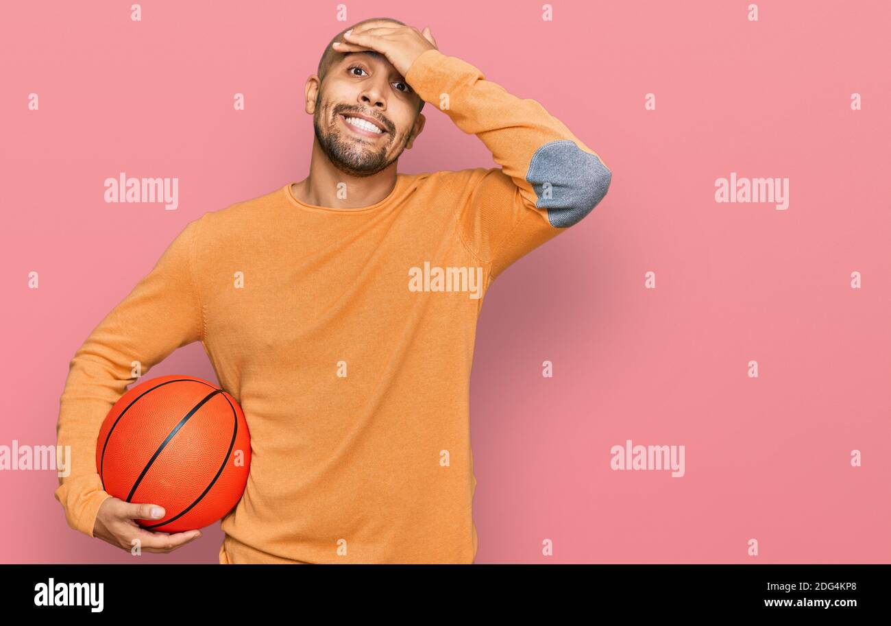 Hispanic adult man holding basketball ball stressed and frustrated with ...