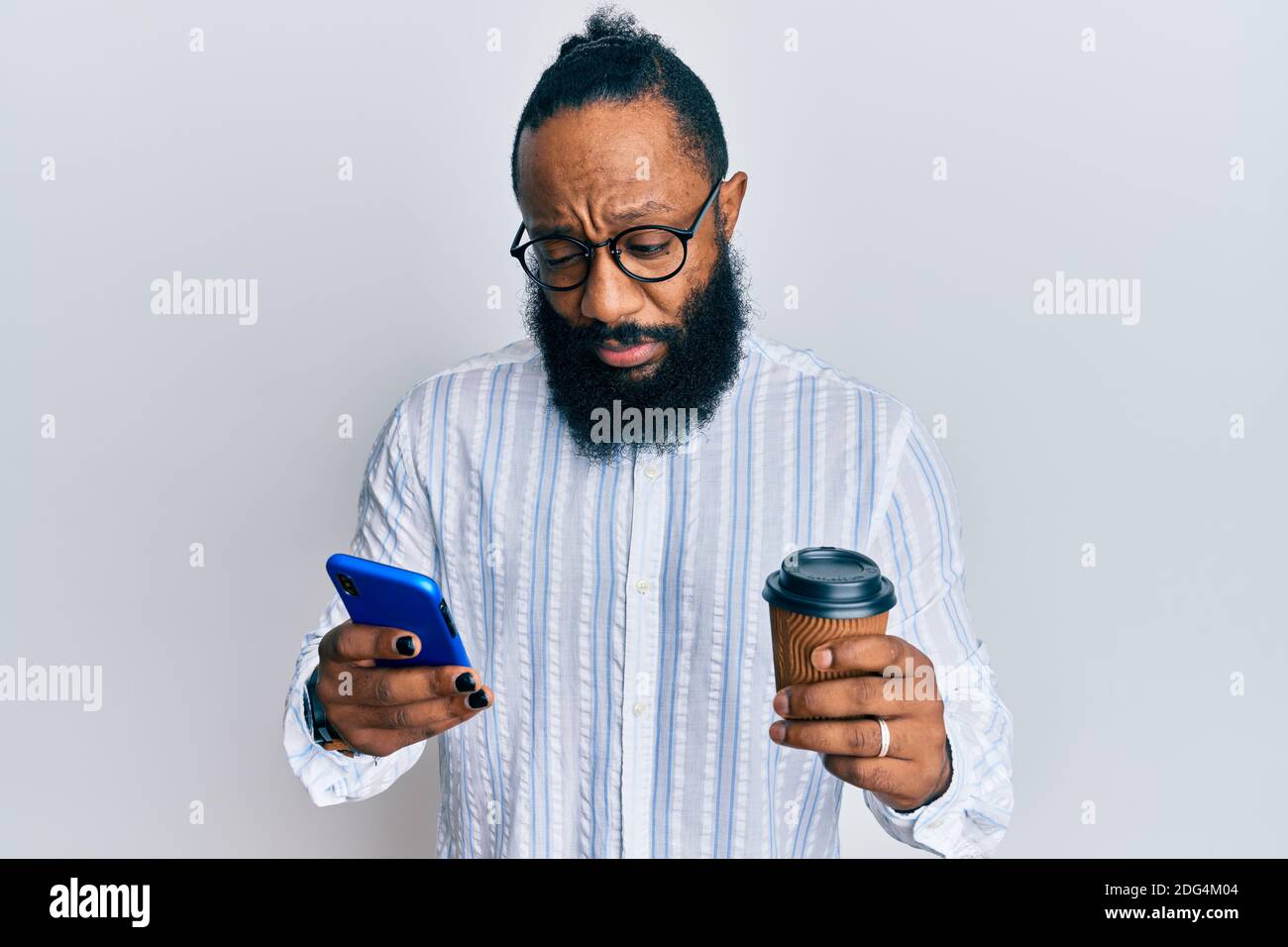 Young african american man using smartphone and drinking a cup of ...