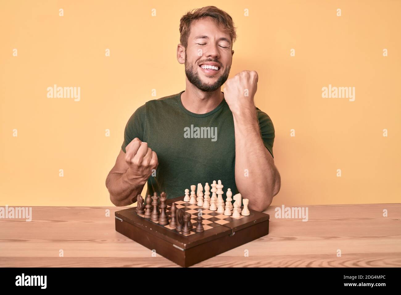 Young caucasian man playing chess sitting on the table celebrating ...