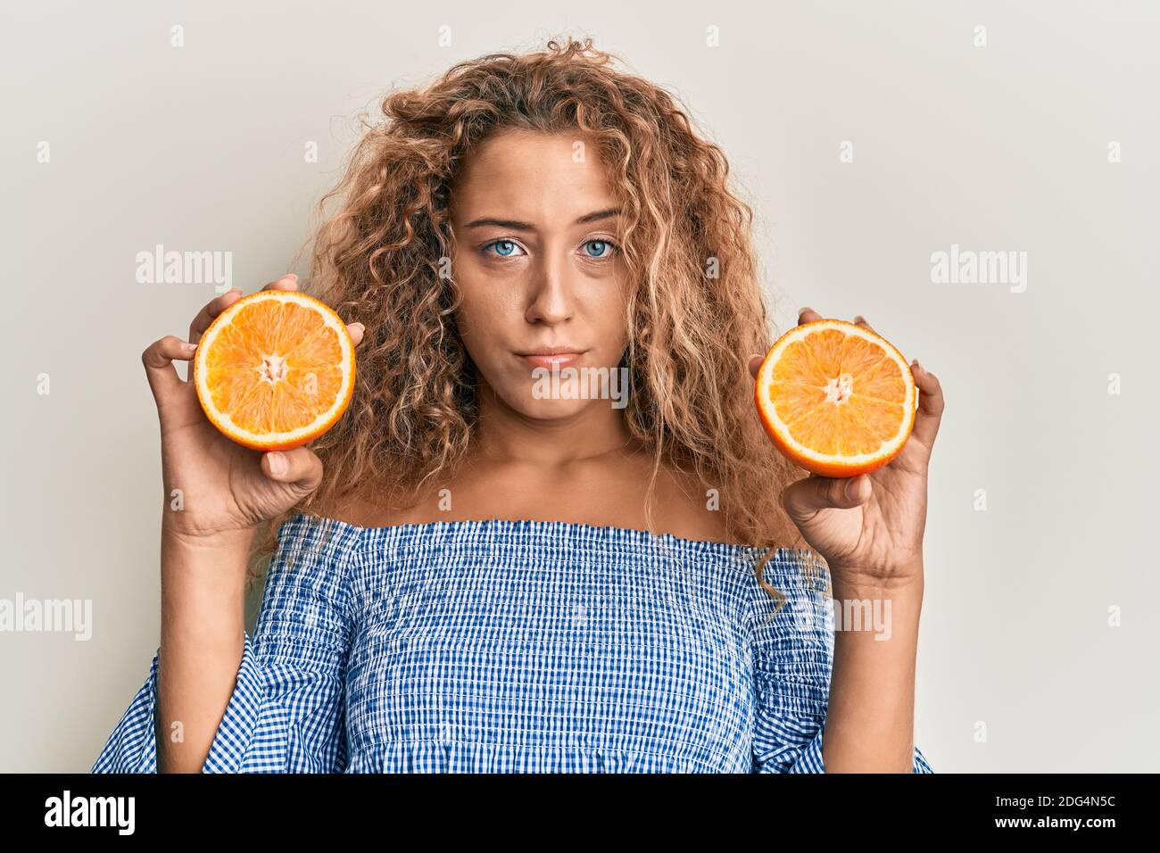 Beautiful caucasian teenager girl holding fresh orange depressed and ...