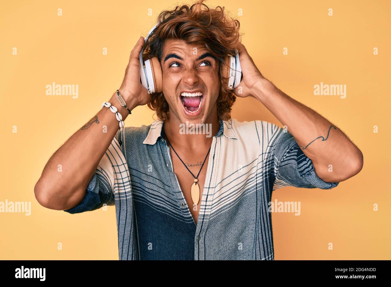 Young hispanic man listening to music using headphones angry and mad ...